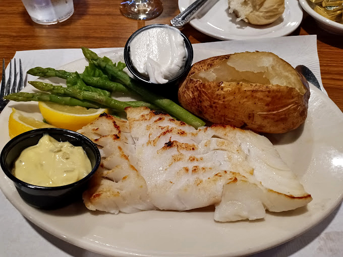 White fish so perfectly cooked it flakes with barely a whisper from your fork, complemented by a loaded baked potato that's an adventure all its own.