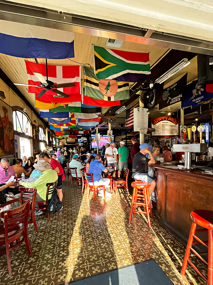 Beneath a ceiling of international flags, patrons gather at the wooden bar where Hemingway himself once rested his elbows.