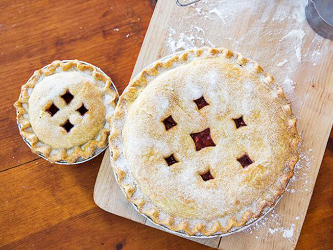 Lattice-topped perfection waiting to be devoured. These handmade pies sit on wooden boards like contestants at a beauty pageant where everyone's a winner.