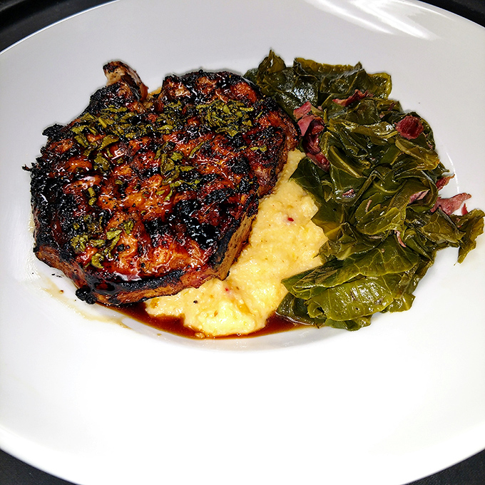 Southern comfort on a plate: tender ribeye resting beside collard greens and creamy grits. A symphony of flavors that sings "North Carolina."