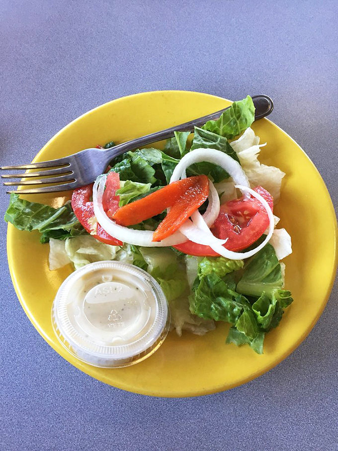 Even the salad looks happy to be here. A bright yellow plate cradles fresh greens &ndash; the token vegetable option for those practicing "balance."