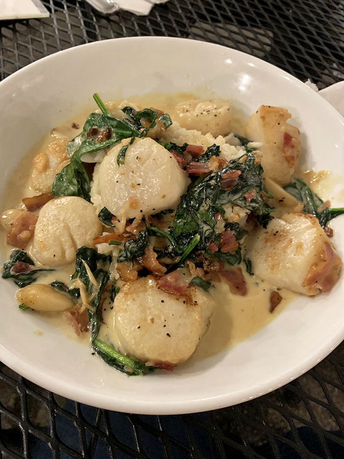 Scallops that would make Neptune himself jealous, perfectly seared and nestled among bacon and greens like pearls in an ocean garden.