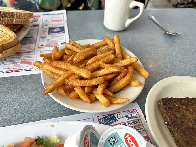 Golden French fries piled high like tiny log cabins of potato perfection&mdash;simple pleasures that remind you why diners endure while trends fade. 
