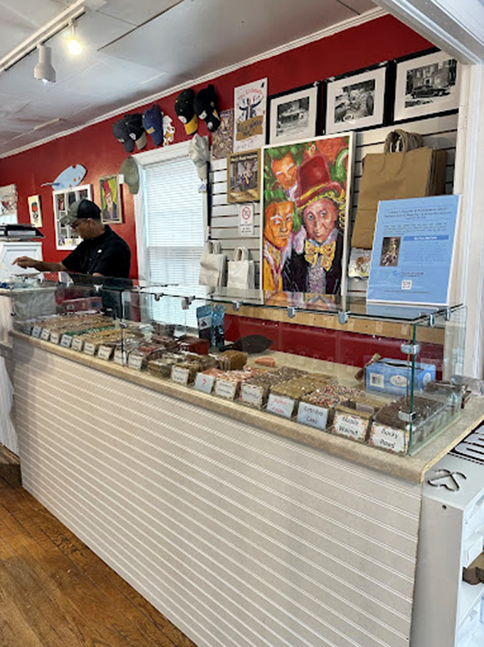 The corner shelves hold a chocolate library where every volume tells a delicious story. The red walls practically pulse with sweet energy.