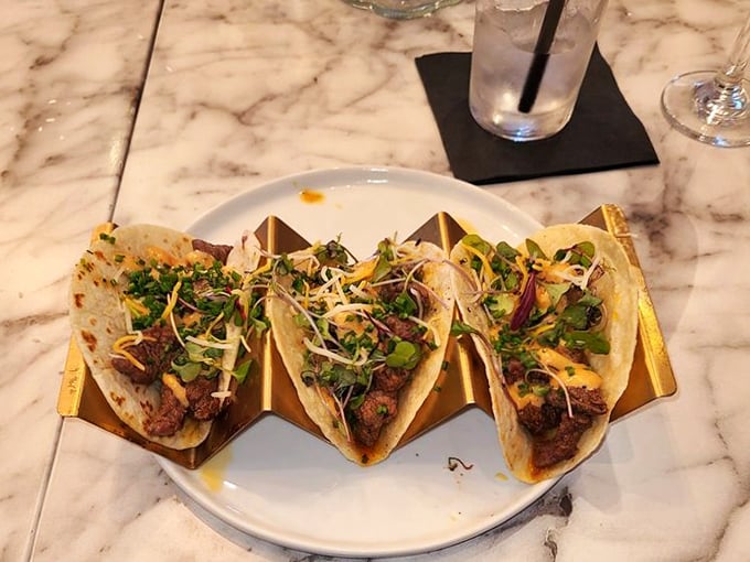 Tacos elevated from handheld convenience to artistic expression. That golden taco holder isn't just for show &ndash; it's a pedestal for deliciousness.