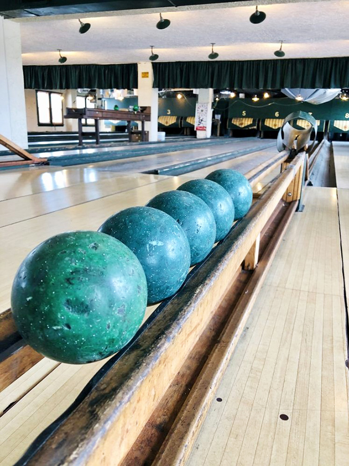 Seafoam green balls lined up like planets, ready for their mission to topple those stubborn duckpins.