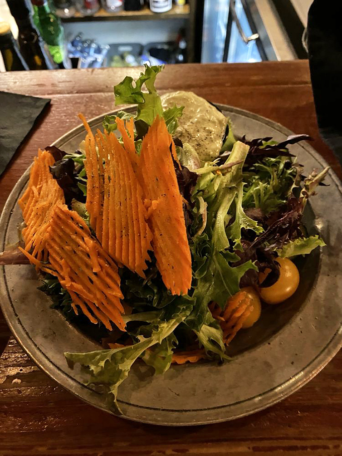 A salad that doesn't apologize for being healthy. Those carrot crisps stand tall like edible modern art, proving vegetables can have personality too.