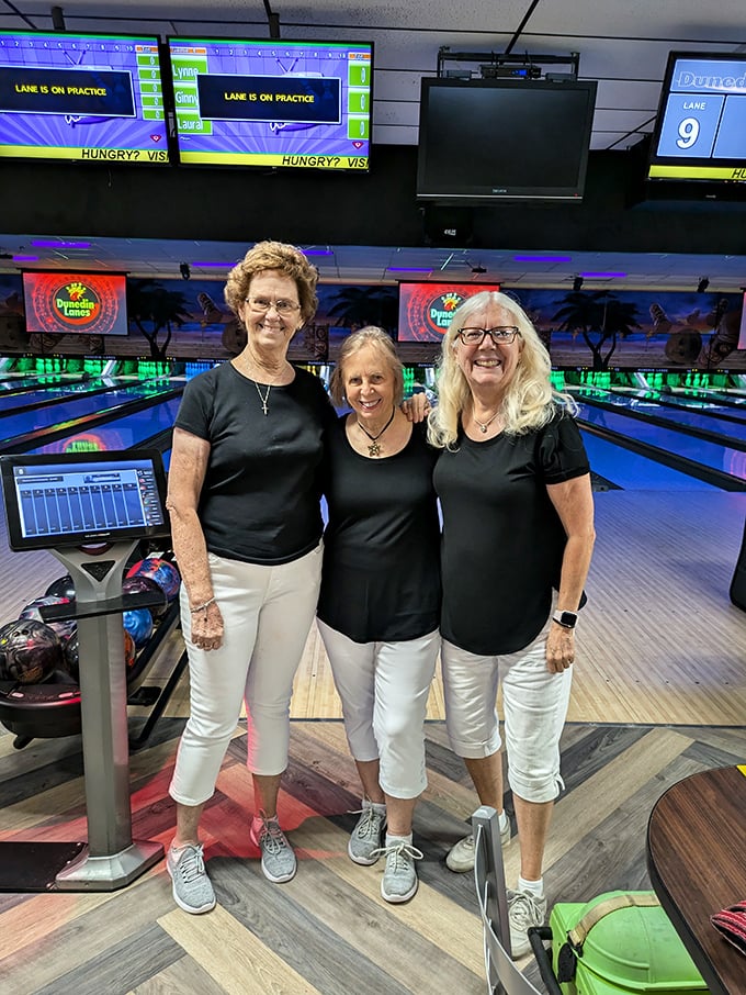 Three friends in matching black shirts demonstrate the timeless bowling alley tradition of team coordination&mdash;on and off the lanes.