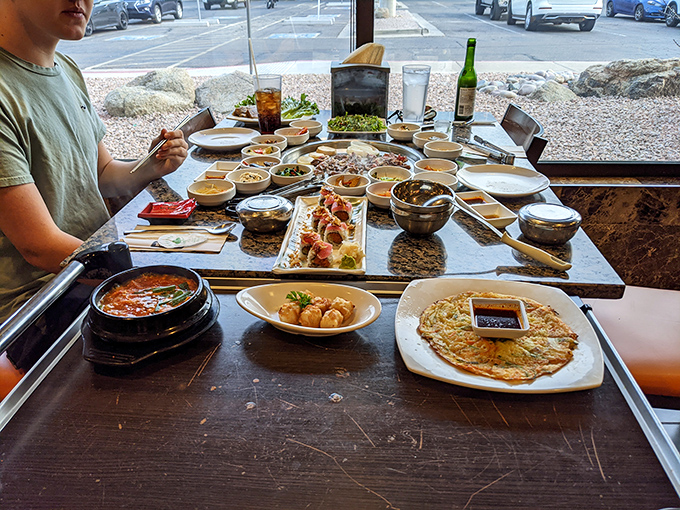The banchan parade: eight little dishes of happiness that make you wonder how pickled vegetables and tiny fish can possibly taste this good.