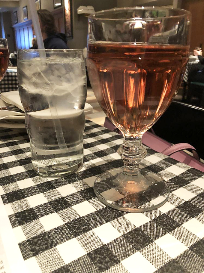 A glass of ros&eacute; and water on classic checkered tablecloths. Sometimes the perfect dining companion isn't conversation&mdash;it's a good glass of wine.