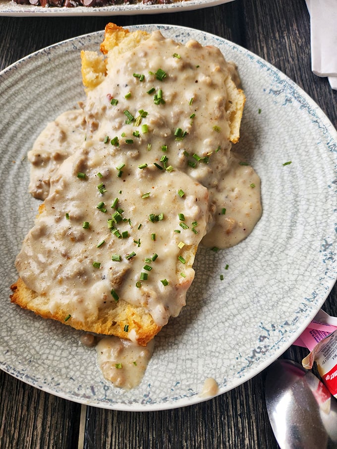 Biscuits and gravy: where Southern comfort food meets artistic expression. Those flecks of chives aren't just garnish&mdash;they're edible confetti celebrating breakfast.