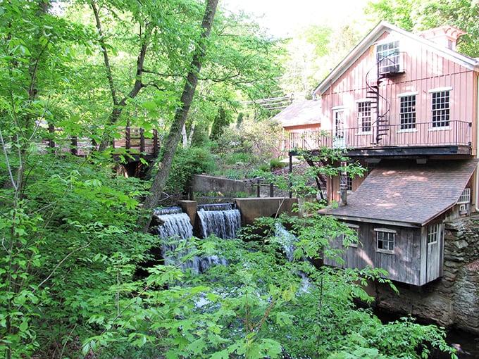 Cascading waterfalls and a rustic pink building with a spiral staircase offer you a serene view amidst the lush greenery.