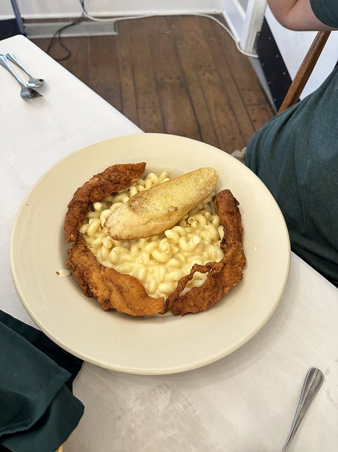 Comfort food paradise: crispy fried chicken strips surrounding creamy mac and cheese&mdash;like a warm hug on a plate. 