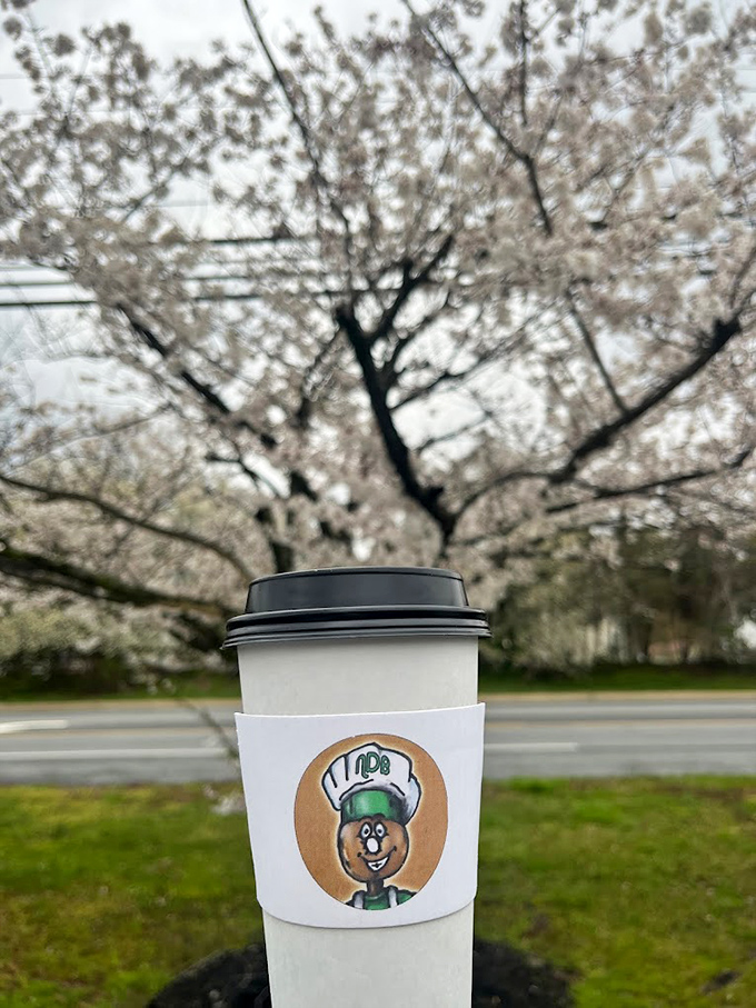 Coffee with the shop's mascot sleeve, enjoyed against a backdrop of spring blossoms&mdash;a moment of zen before the day begins.