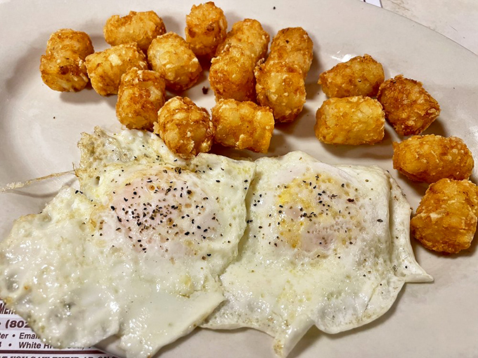 Two sunny-side up eggs keeping watch over golden tater tots—a breakfast that says "good morning" with the enthusiasm of a golden retriever.