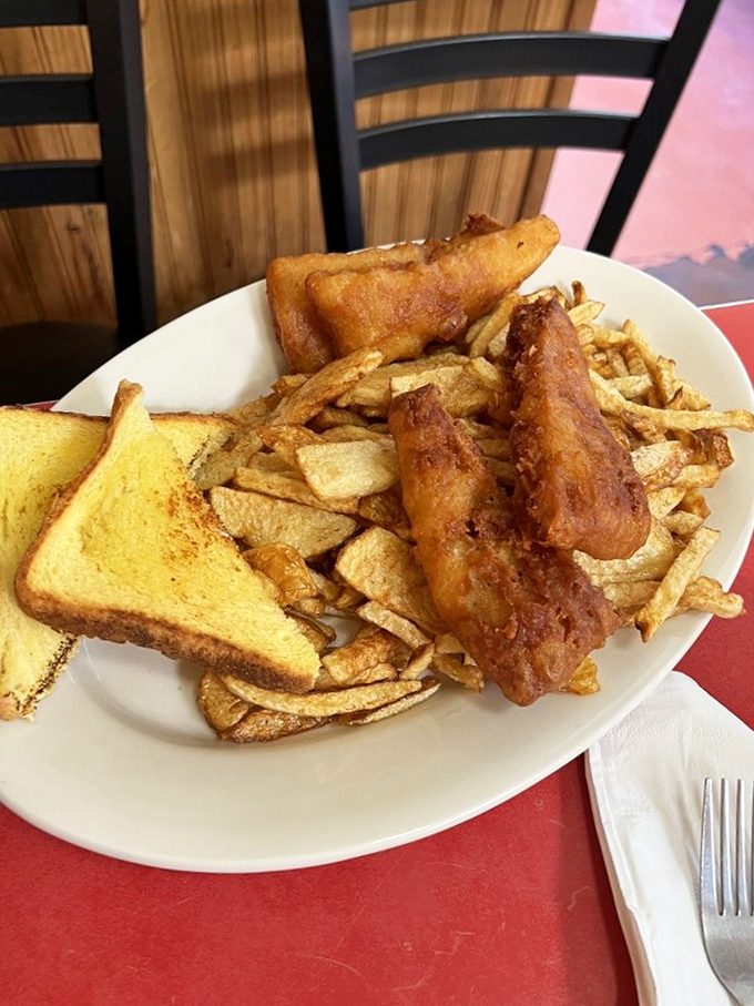Comfort on a plate: golden-battered fish, a mountain of fries, and the kind of toast that reminds you why butter was invented.