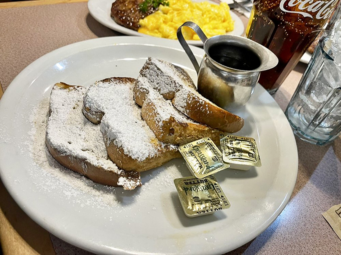French toast that's dressed for success with a snowfall of powdered sugar. The maple syrup stands by, ready for its supporting role in this breakfast blockbuster.
