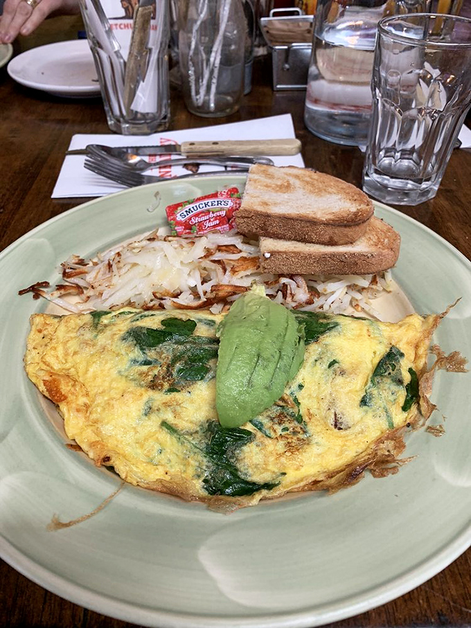An omelet that's dressed better than most people at breakfast &ndash; spinach-filled, cheese-draped, and crowned with slices of avocado like nature's butter.