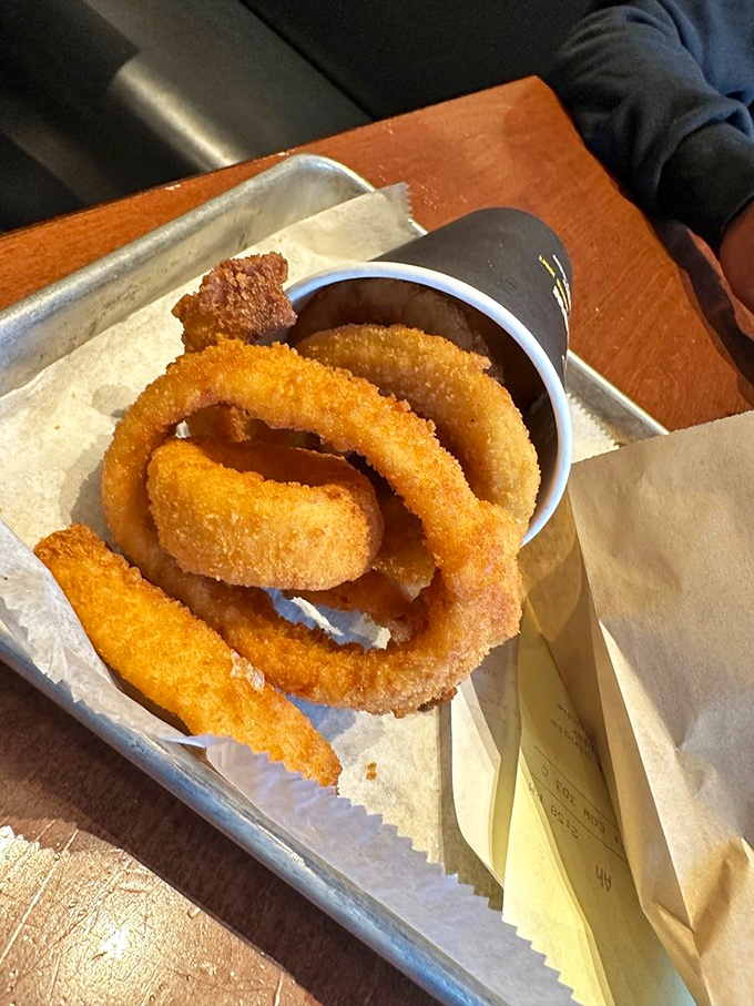 Onion rings that deserve their own zip code. Thick-cut, beer-battered circles of joy that make you forget vegetables are supposed to be healthy.