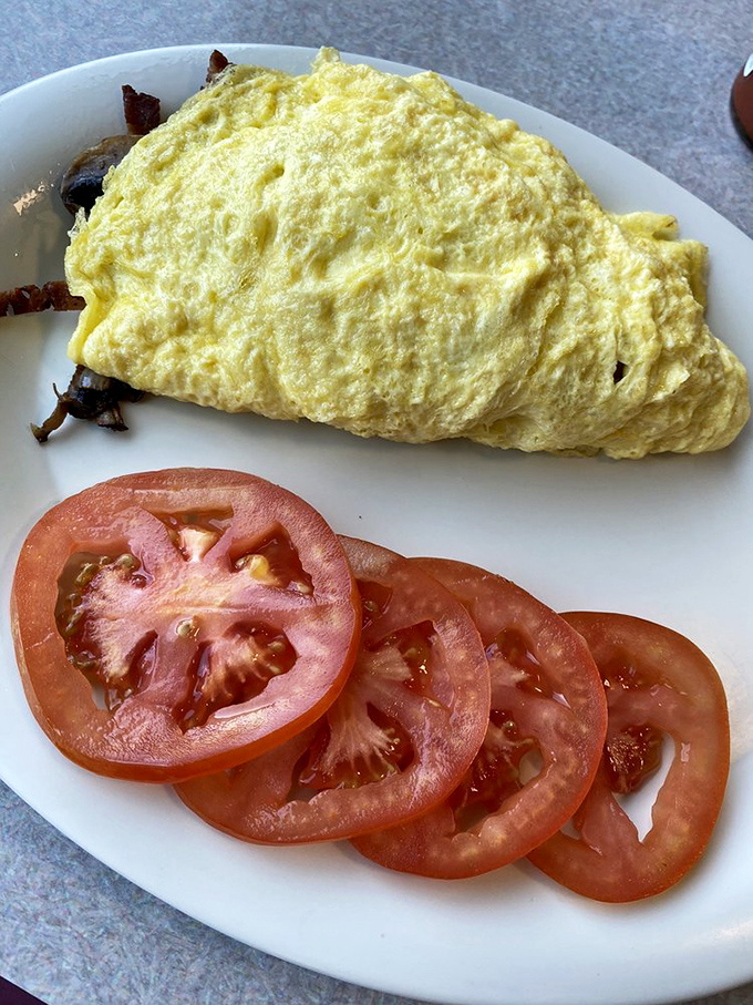 The Oregon Omelet unfolds like a yellow sunrise, stuffed with local ingredients and paired with tomato slices that actually taste like tomatoes.