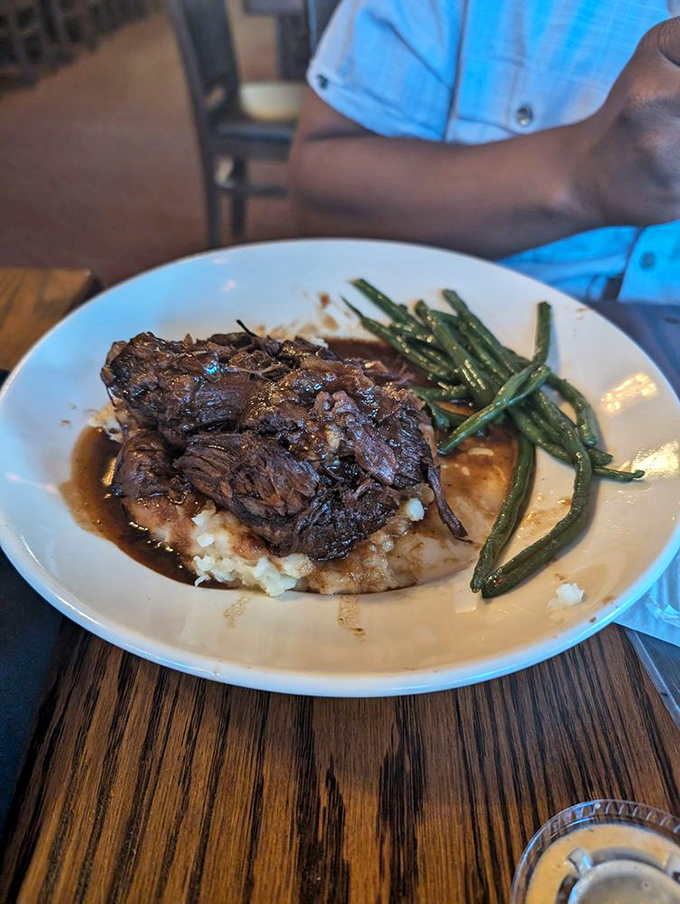 Surrender to the slow-cooked short ribs that collapse at the mere suggestion of your fork, lounging on a cloud of mashed potatoes like they own the place.