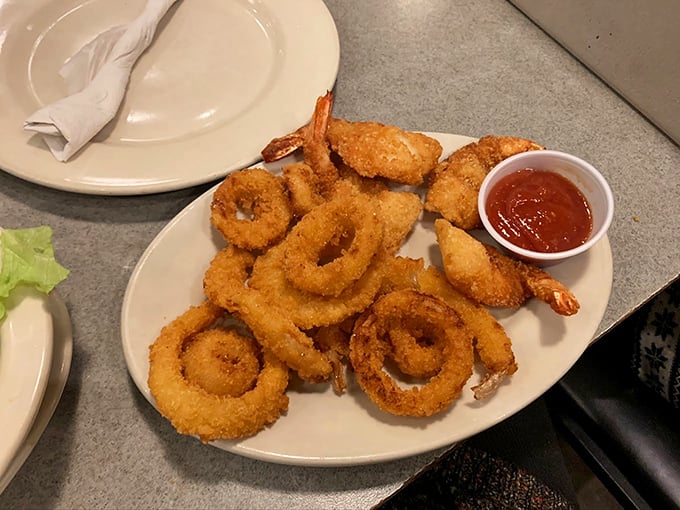 Crispy onion rings and golden shrimp sharing a plate like old friends, with cocktail sauce playing matchmaker on the side.