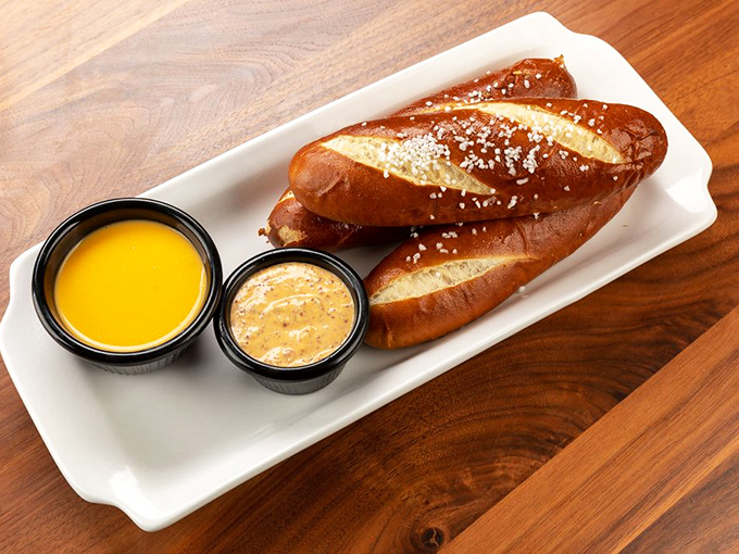 These aren't just pretzels; they're glistening carb sculptures served with dipping sauces that make you question why you'd eat them any other way.