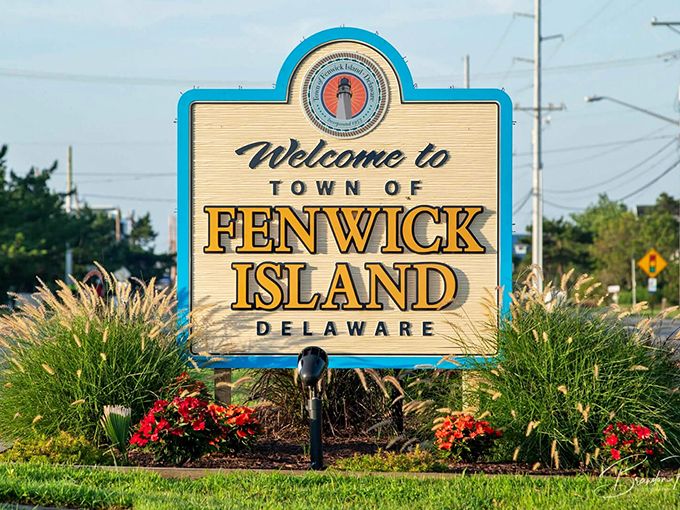 The town welcome sign greets visitors with coastal charm, surrounded by sea grasses dancing in the Atlantic breeze.