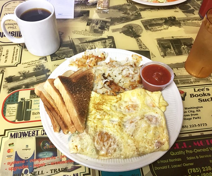 Breakfast of champions – eggs, toast, and hash browns on plates that have seen thousands of hungry mornings. The coffee cup stands ready for refills.