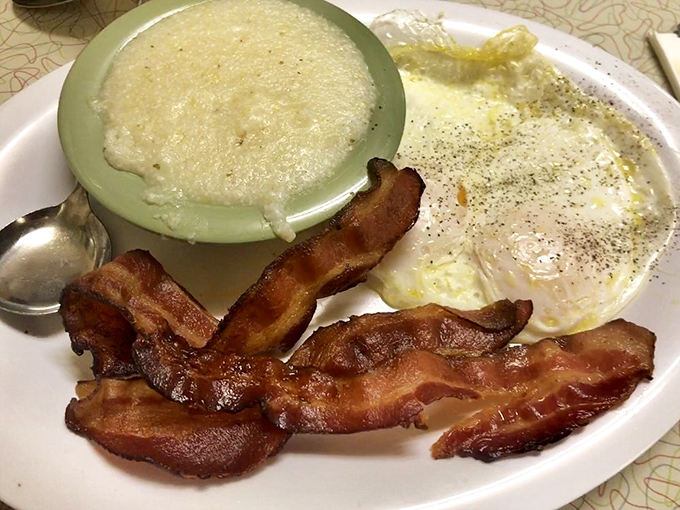 The holy trinity of breakfast perfection: creamy grits, perfectly fried eggs, and bacon cooked to that magical point between chewy and crisp.