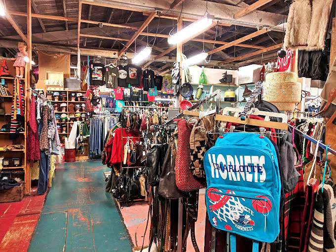 A vintage Hornets backpack hangs among leather jackets and colorful clothing, proving one shopper's throwaway is another's treasure. 