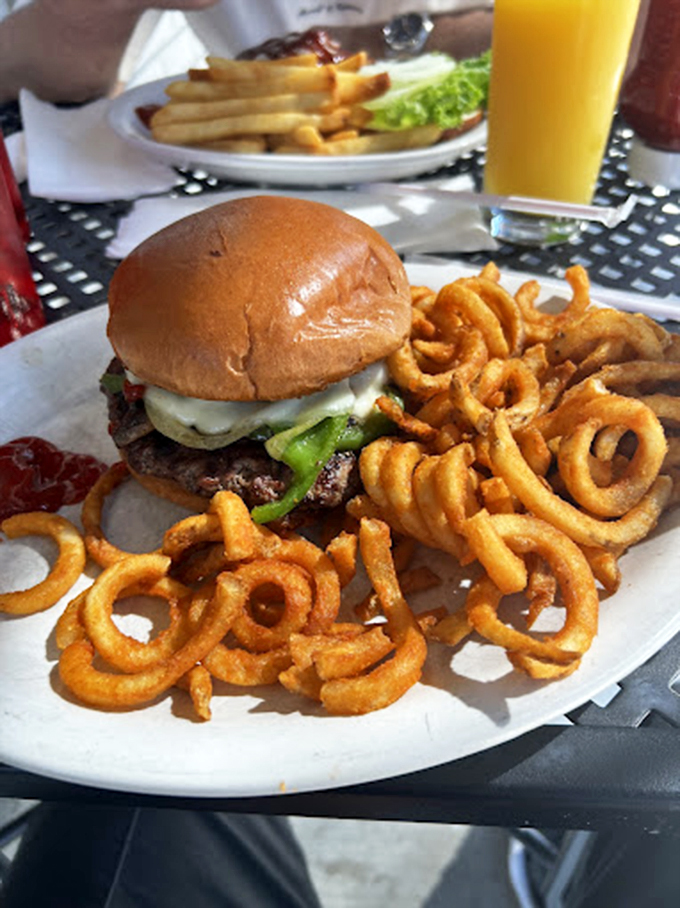 A burger that requires a game plan before the first bite, surrounded by curly fries that could double as edible Slinkys.