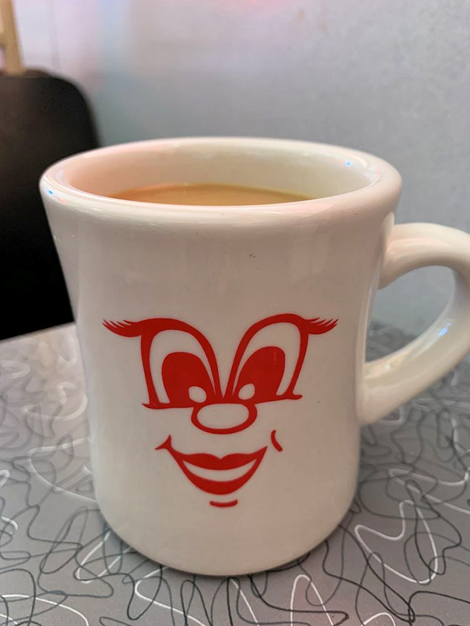 The coffee mug grins because it knows what you need before you do. In diners, coffee isn't just a beverage&mdash;it's emotional support.