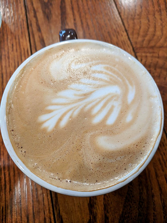 Latte art so pretty you almost don't want to drink it. Almost. The wooden table adds that perfect rustic touch to your caffeine ritual.