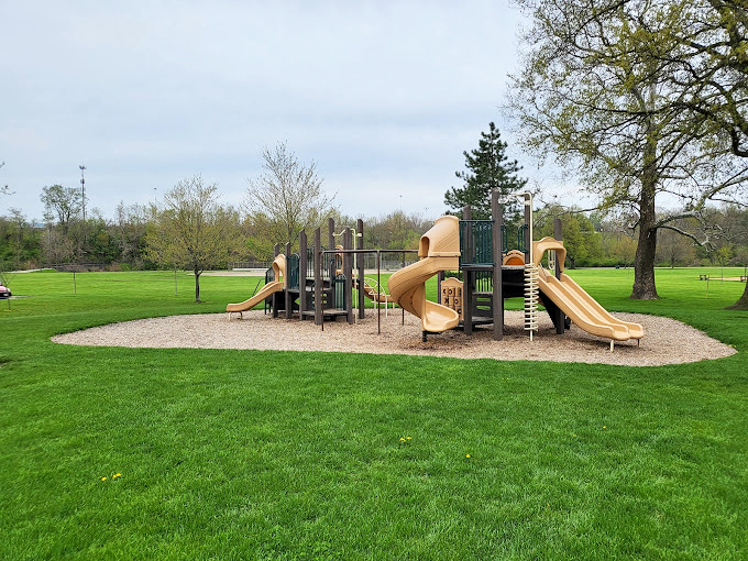 Childhood joy comes standard at this playground where slides and climbing structures await young explorers while parents enjoy the surrounding greenery.