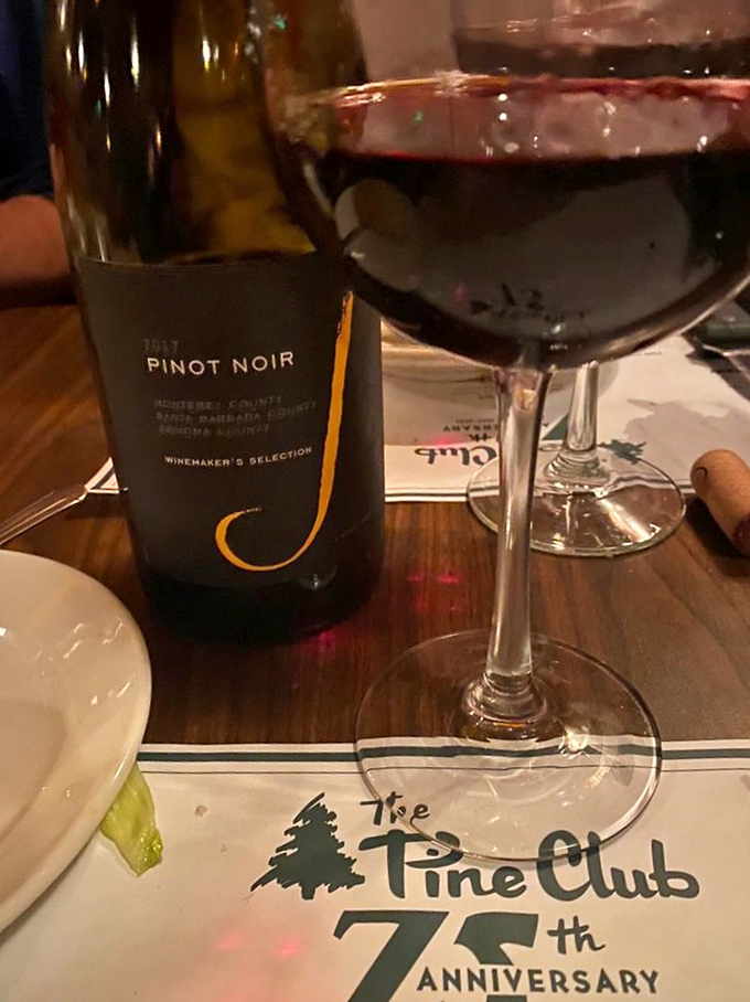 A glass of Pinot Noir catches the light as it celebrates The Pine Club's 75th anniversary. Some relationships are worth toasting.
