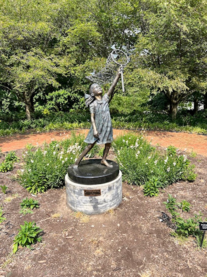 This bronze girl reaches skyward, forever caught in a moment of wonder. Childhood curiosity immortalized in metal&mdash;no batteries required.