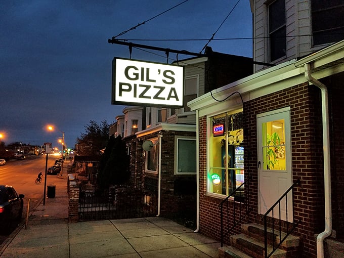 As night falls, Gil's glowing window becomes a beacon of hope for the pizza-deprived. Salvation by the slice.