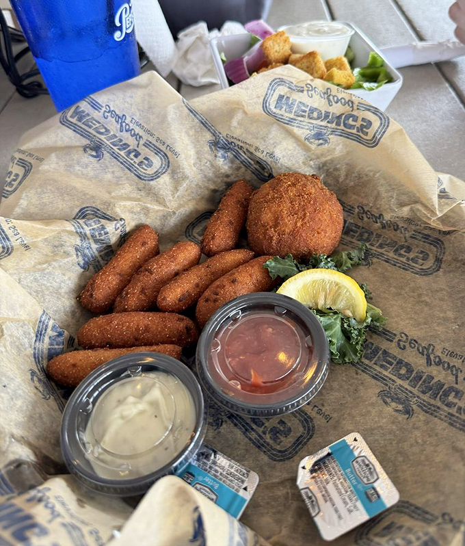 Hush puppies and crab cakes served on branded paper&mdash;a humble presentation for flavors that are anything but modest.