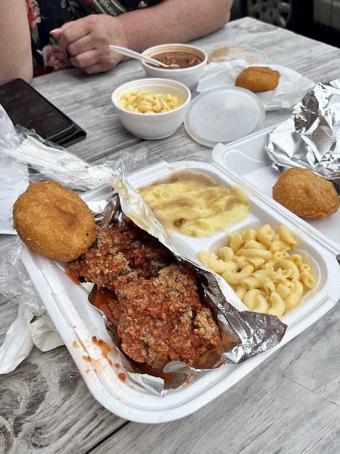 Meatloaf that would make your grandmother simultaneously proud and jealous, flanked by mac and cheese that demands to be the center of attention.