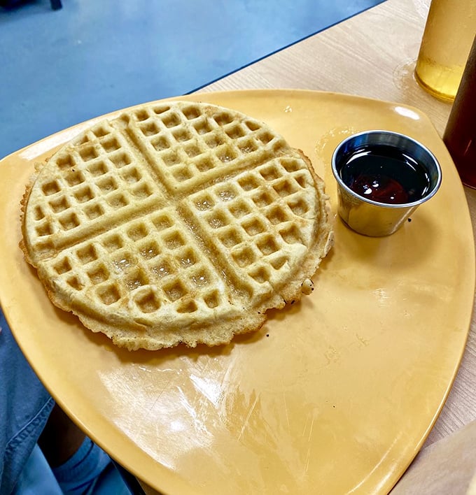 This waffle isn't just breakfast&mdash;it's a golden canvas awaiting its maple syrup masterpiece, served on a plate that matches its sunny disposition.