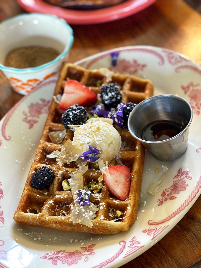 A waffle that's dressed for success with berries, cream, and what appears to be edible flowers. Breakfast or art installation? The debate continues with every bite.