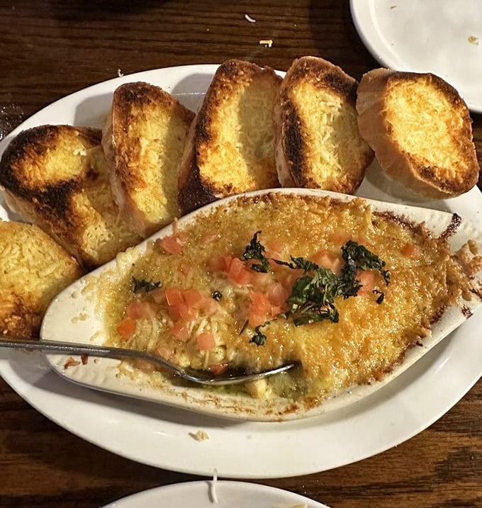 The artichoke dip arrives bubbling like a delicious volcano, with toasted bread standing by for the perfect scoop-to-mouth delivery system.