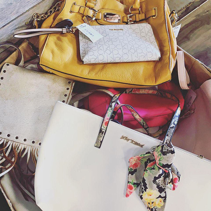 Designer bags huddle together like old friends at a reunion. That yellow Michael Kors might cost less than your lunch, but nobody needs to know.