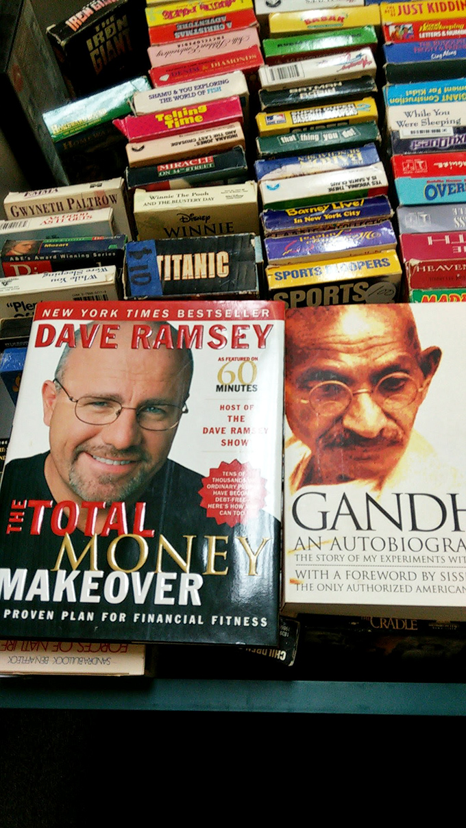 Dave Ramsey and Gandhi sharing shelf space&mdash;a philosophical pairing that perfectly captures the delightful randomness of thrift store book sections.