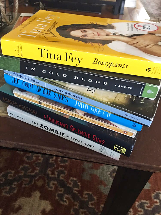 Literary treasures stacked and waiting. From Tina Fey's wit to zombie survival tactics&mdash;this pile represents the beautiful randomness of thrift store book hunting.