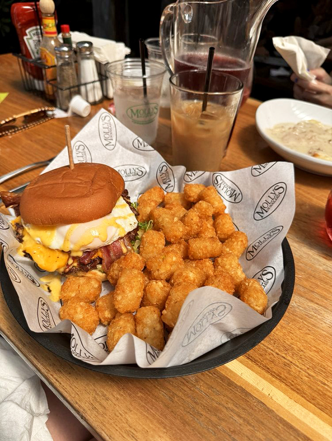 The ultimate hangover cure: a perfectly grilled burger topped with a sunny egg, partnered with golden tater tots that crunch with each bite.