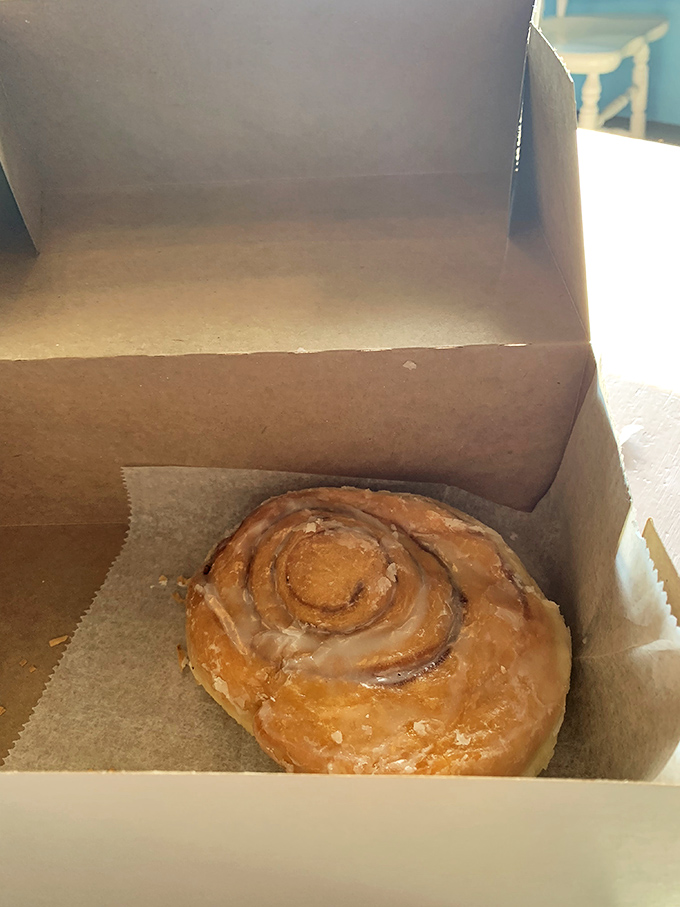 The humble cinnamon roll, perfectly spiraled and glazed, waits patiently in its box. Morning comfort food at its most seductive.