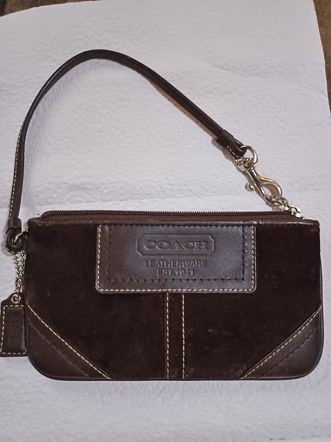 A genuine Coach wristlet awaits its next owner—proof that designer dreams can come true on a thrift store budget.