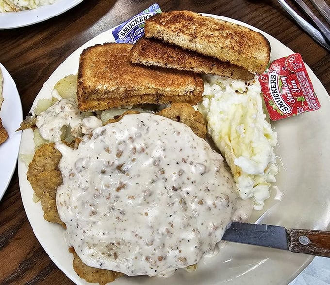 Country fried steak swimming in peppery gravy with toast standing by for the inevitable (and necessary) plate-cleaning operation.